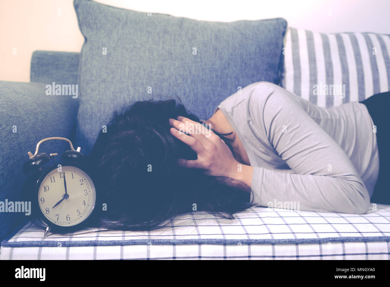 Lazy women are laying down on the sofa after the clock alarm, late ...