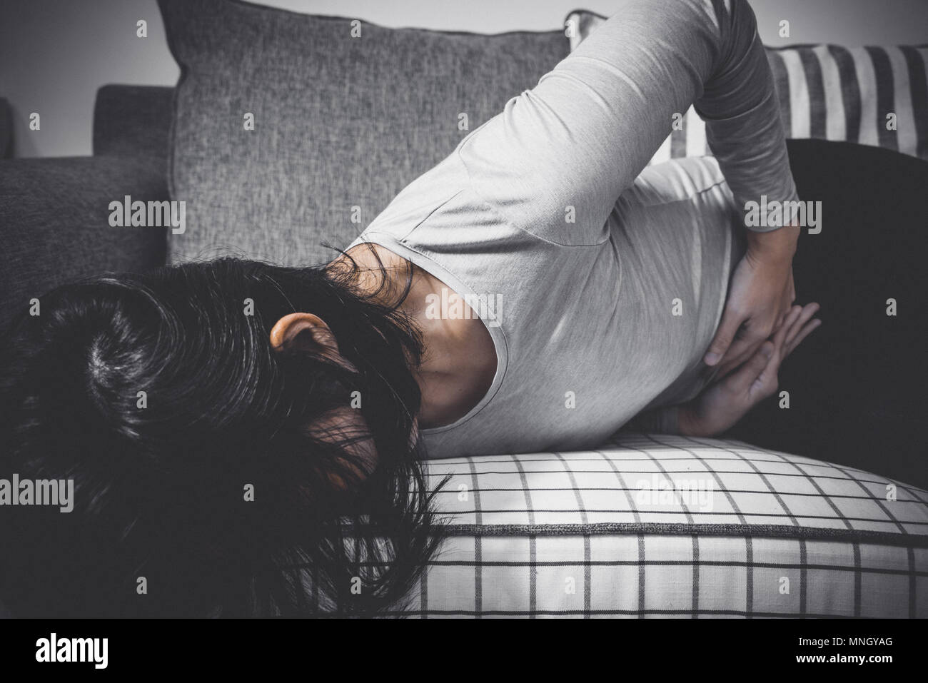 a sad women lay down on the sofa and feeling stomachache, symptom of ...