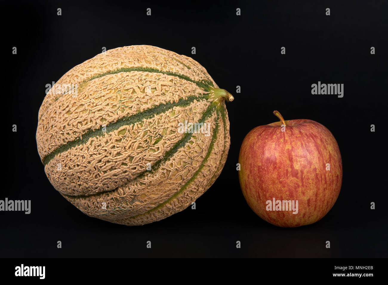 a melon and an apple on a black background Stock Photo - Alamy