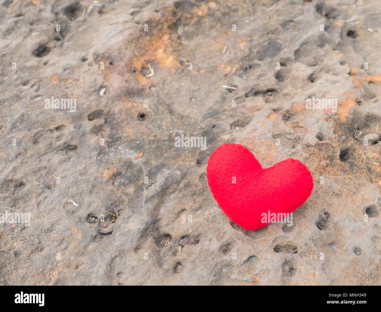 Red heart on rock background Stock Photo - Alamy