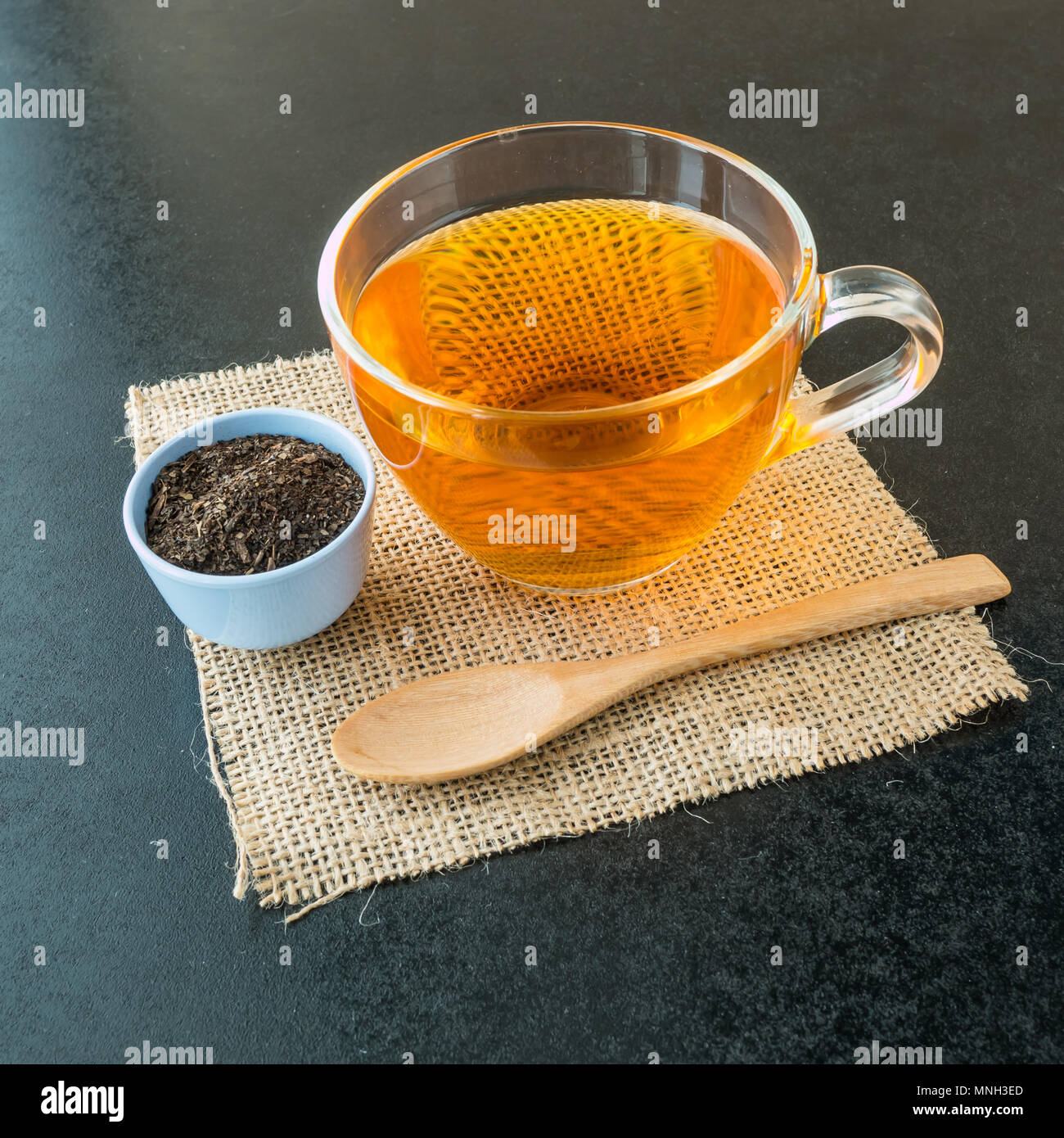 Raw tea in blue cup and Hot tea in glass on black background Stock ...
