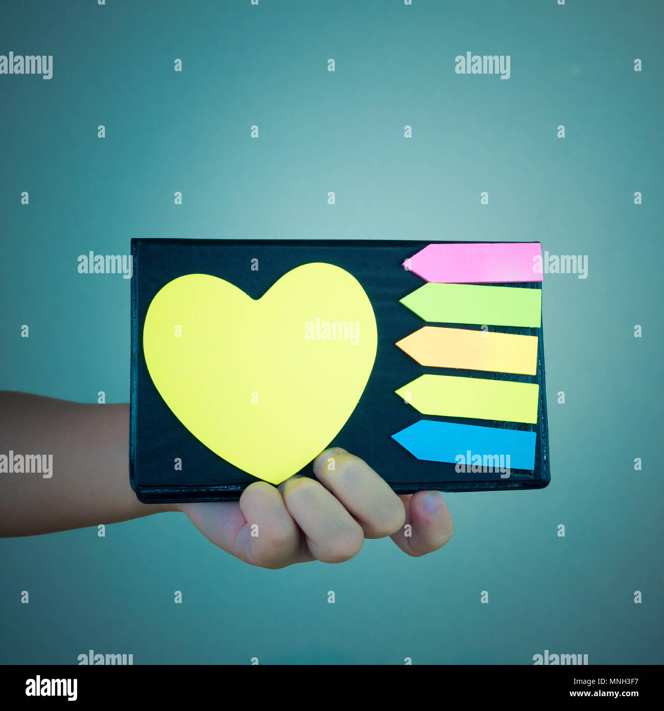 post it note in hand on wall background, yellow heart in hand Stock ...