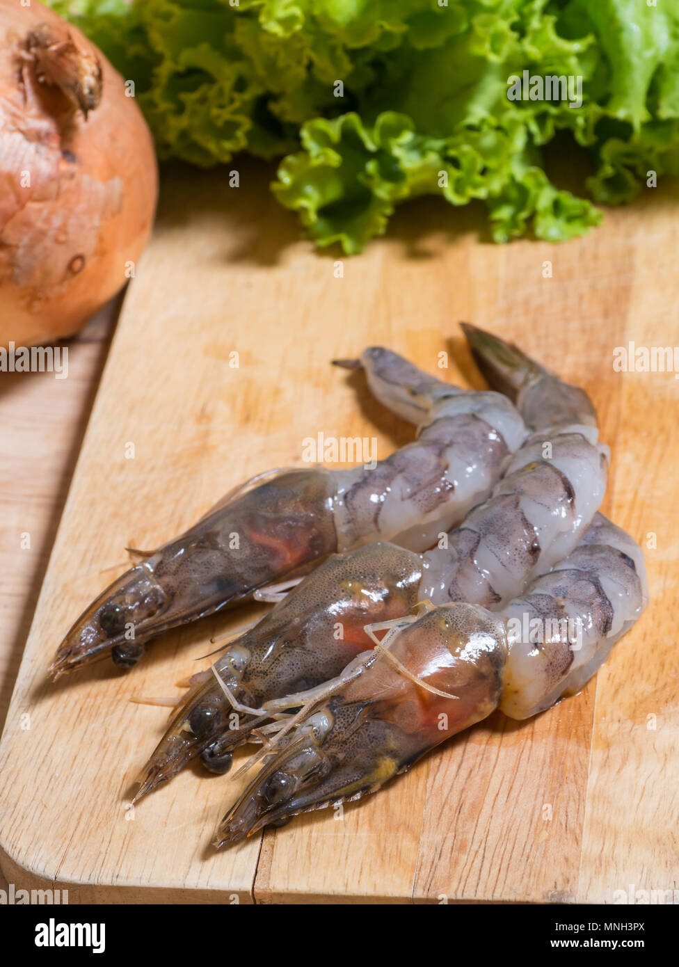 Fresh shrimp in chopping block on vegetable background Stock Photo - Alamy