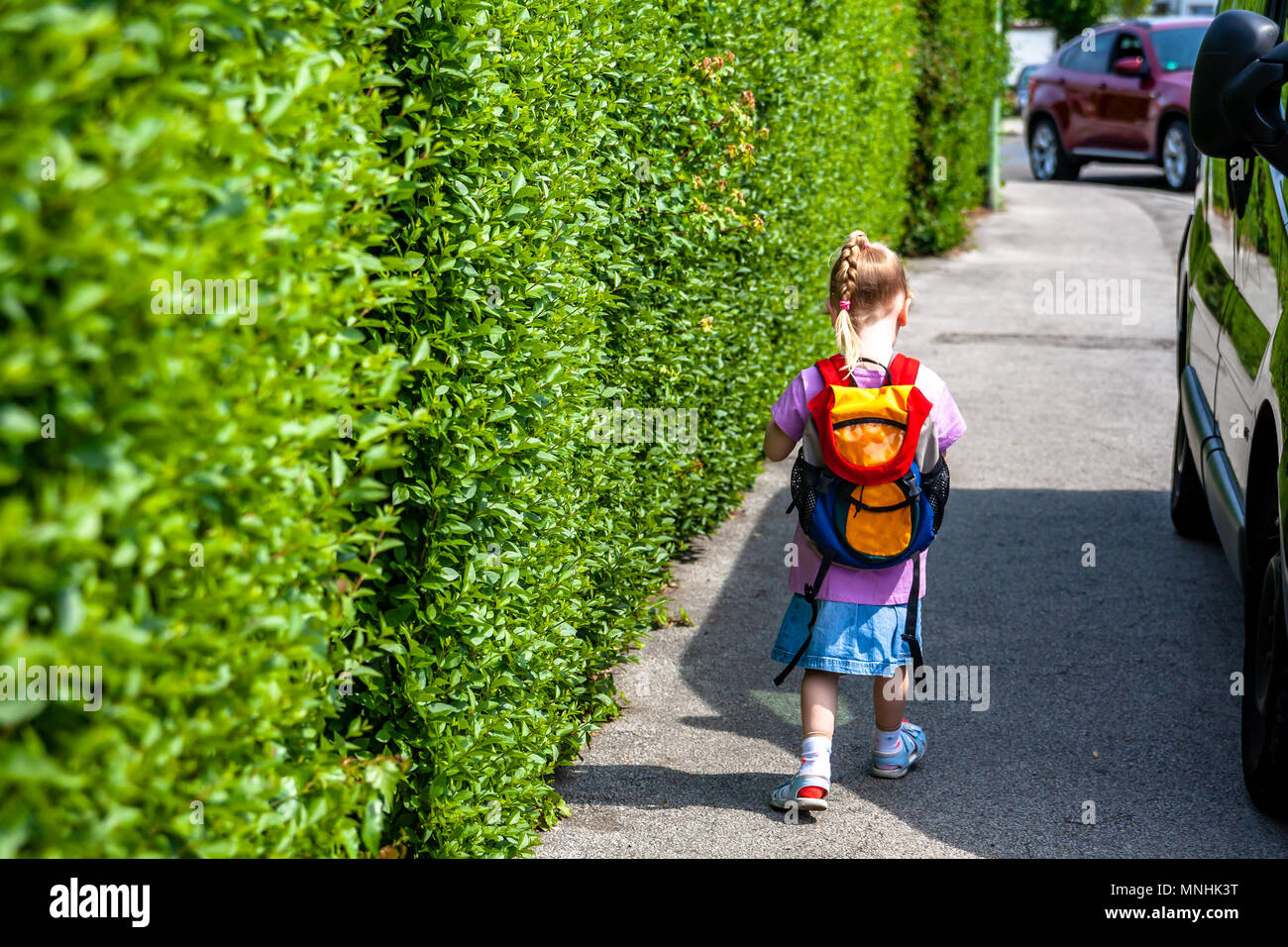 Little girls walking away with her filled backpack Stock Photo - Alamy