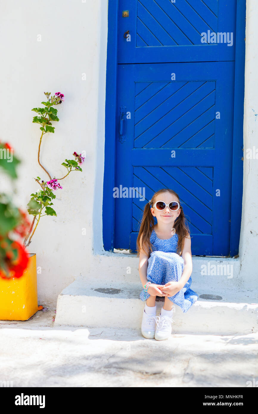 Charming little girl at typical greek traditional village with white ...