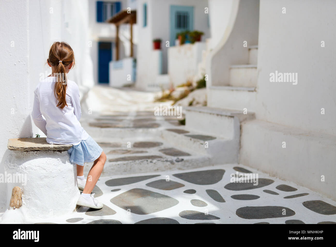 Charming little girl at typical greek traditional village with white ...