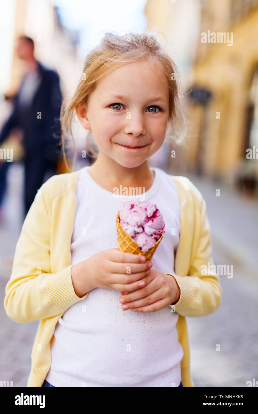 Adorable little girl eating ice cream in a fresh waffle cone outdoors ...