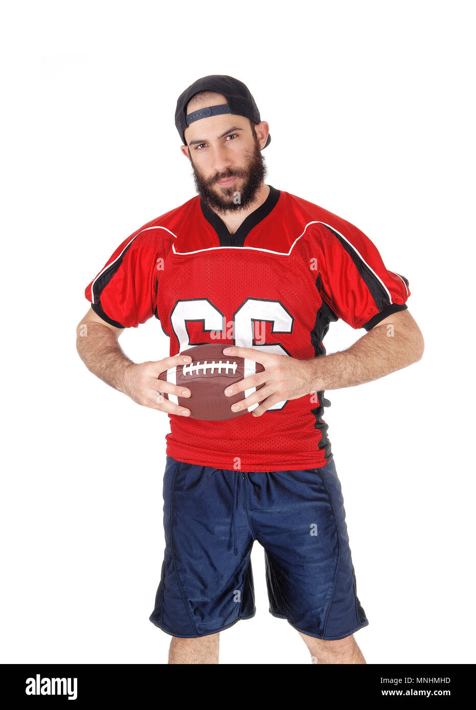 A handsome young football player standing with his ball in his hand ...