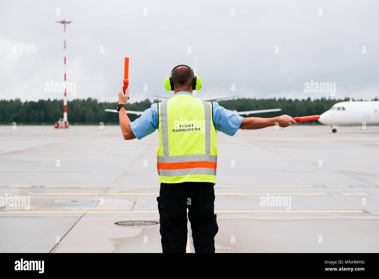 Flight coordinator is guiding an airplane to its parking spot at the ...