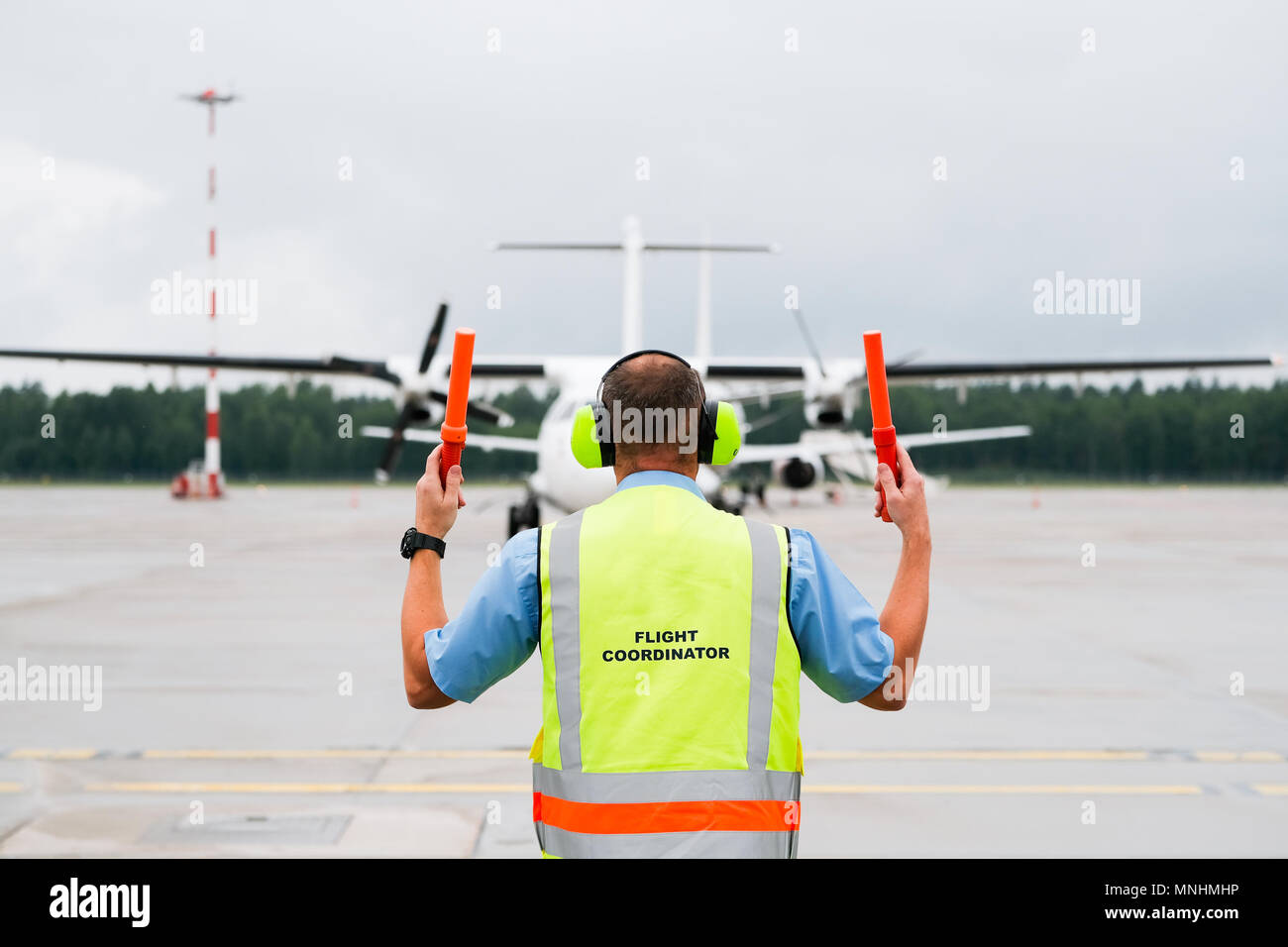 Flight coordinator is guiding an airplane to its parking spot at the ...