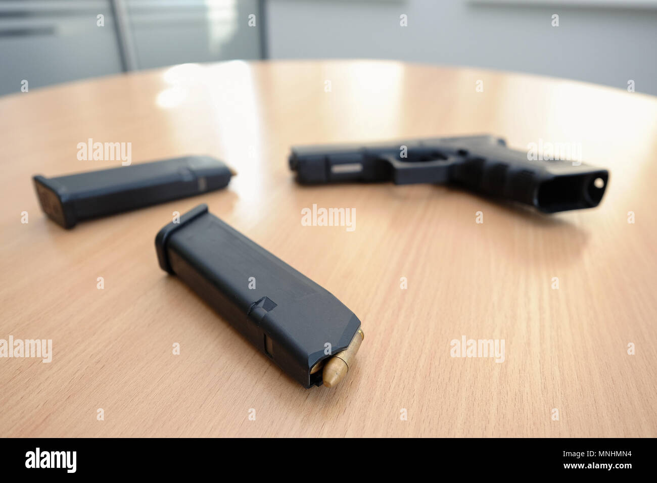 Two loaded handgun magazines are displayed on a table with unloaded ...