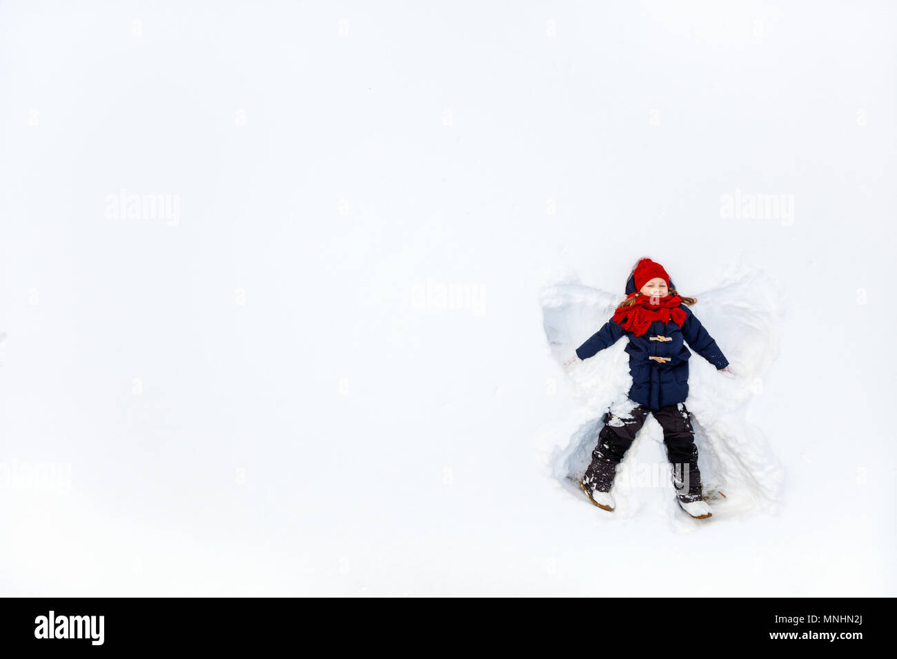 Above view of adorable little girl enjoying beautiful winter day making ...