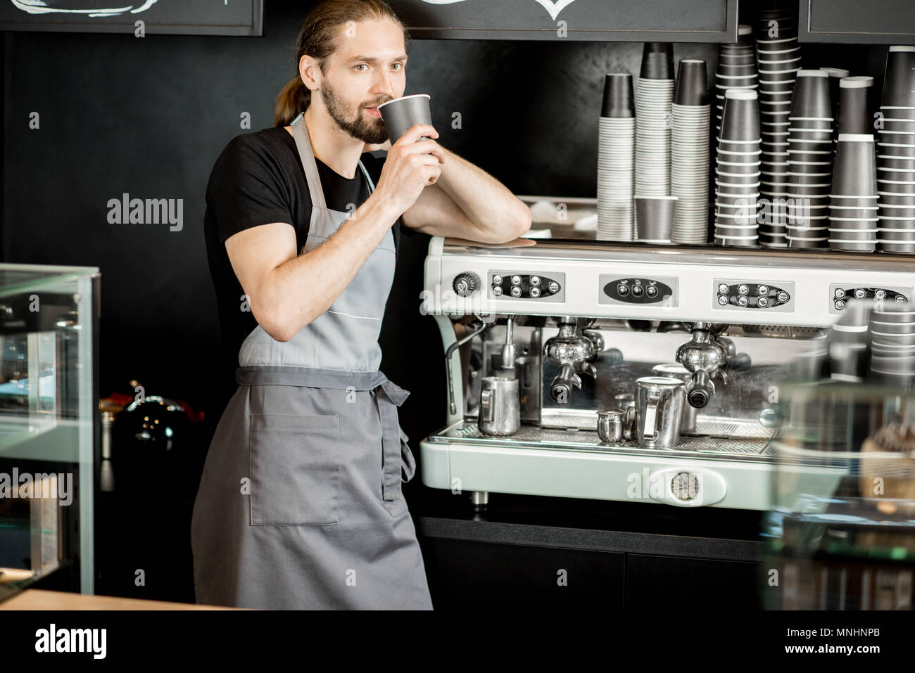 Portrait of a handsome barista in uniform standing near the coffee ...