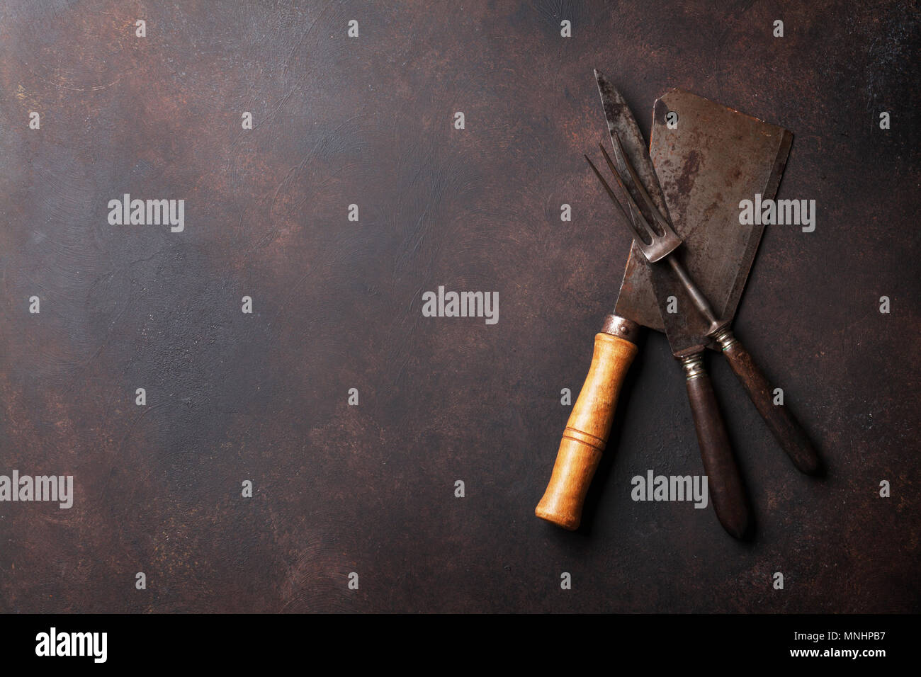 Butcher and kitchen utensils. Vintage meat cleaver, knife and fork over ...