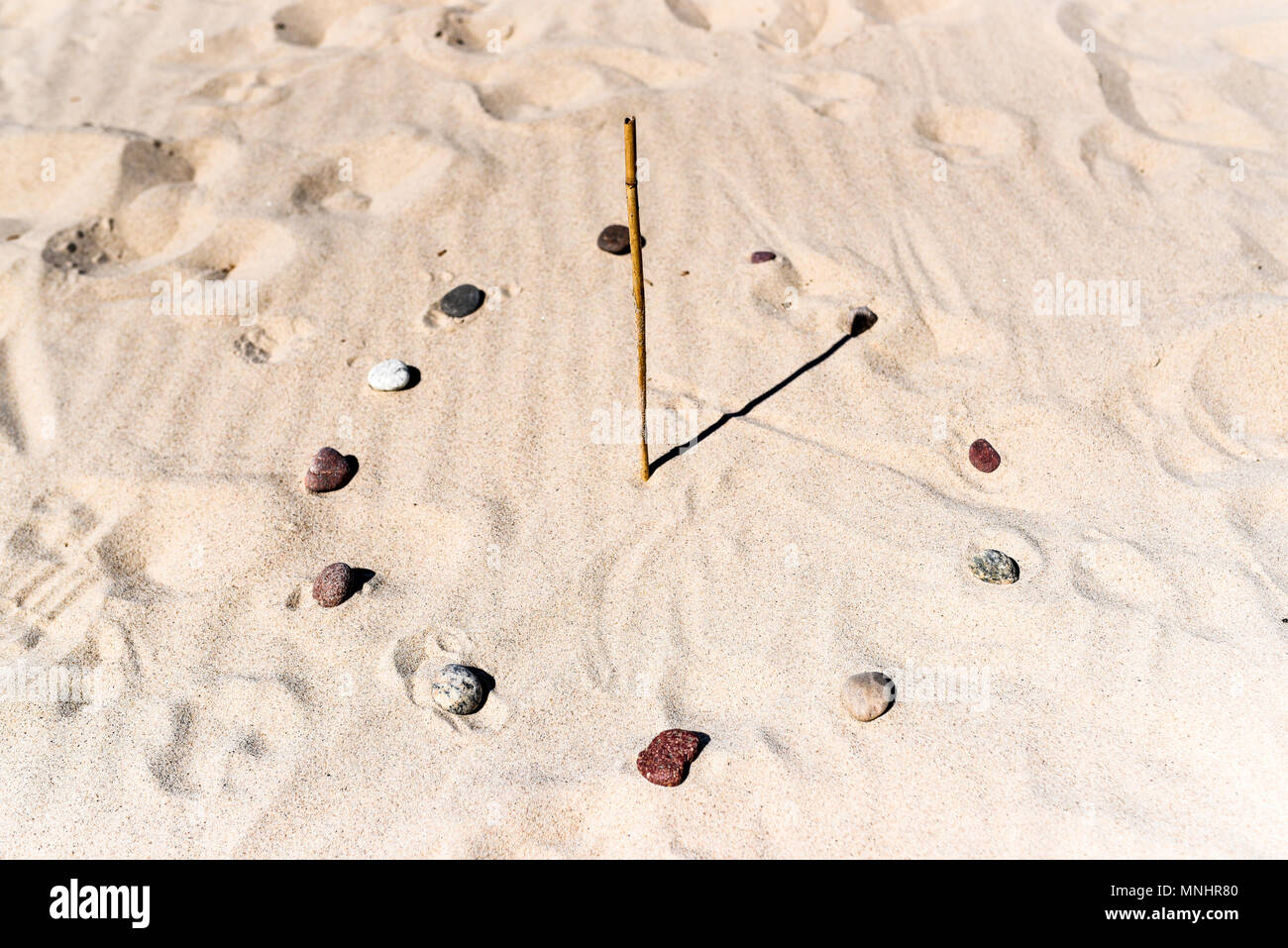 Sundial on the beach made of a stick and stones Stock Photo - Alamy
