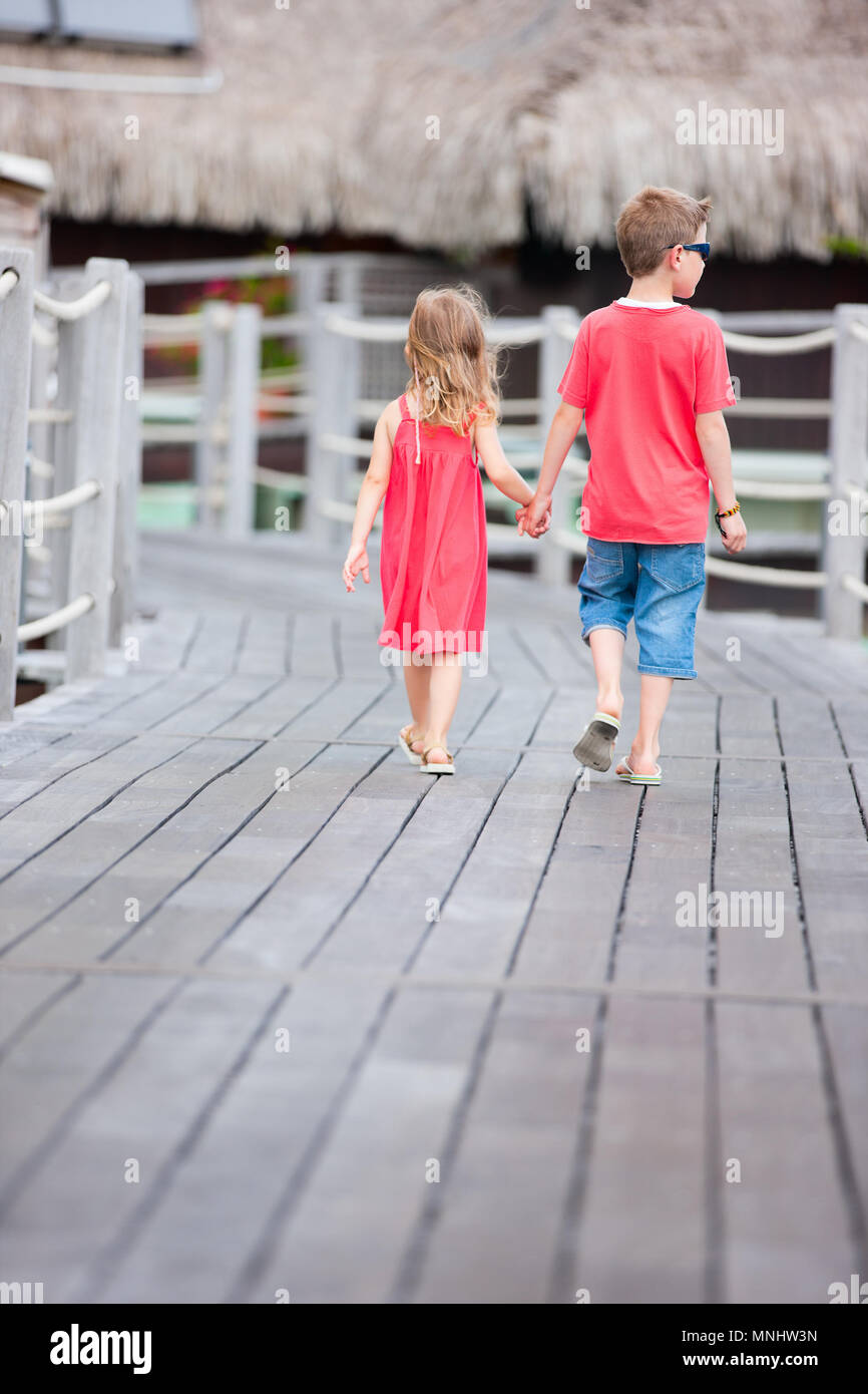 Back view of two kids walking towards over the water bungalows Stock ...
