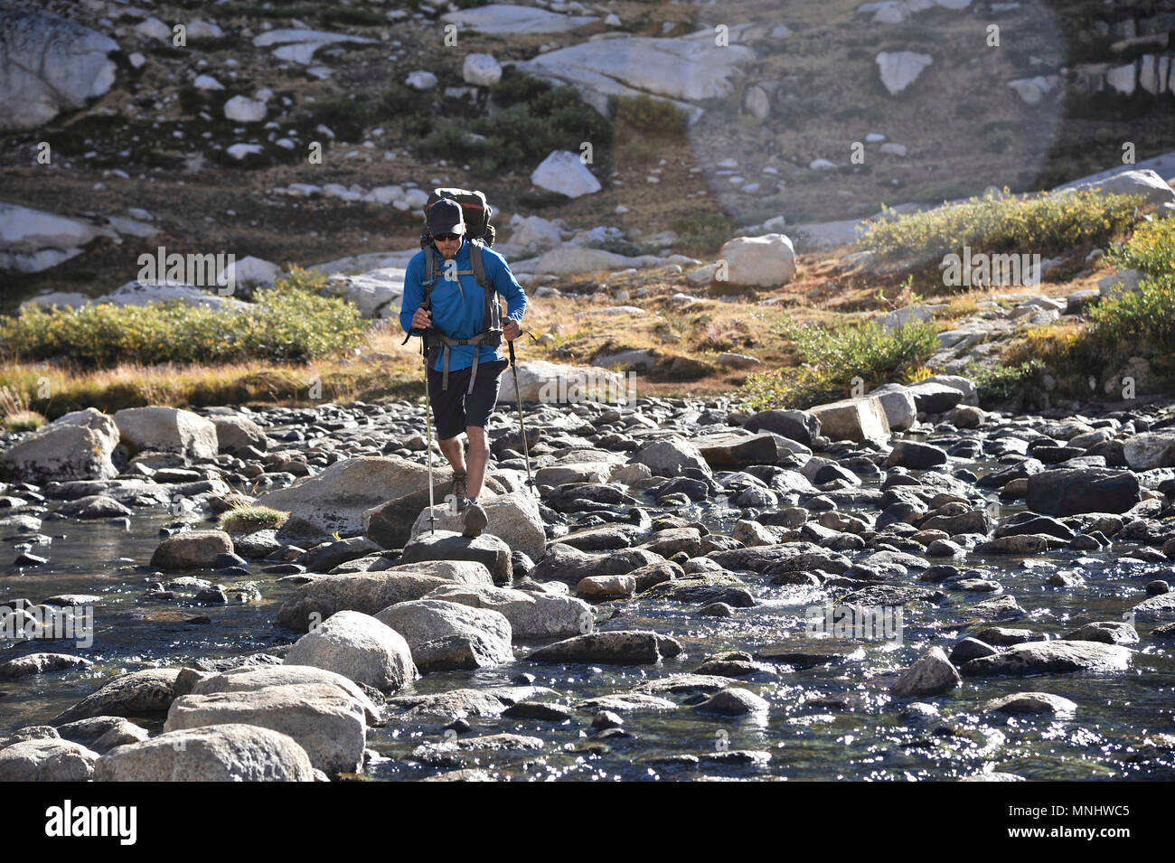 Backpacker hiking the John Muir Trail across Evolution Lake in the ...