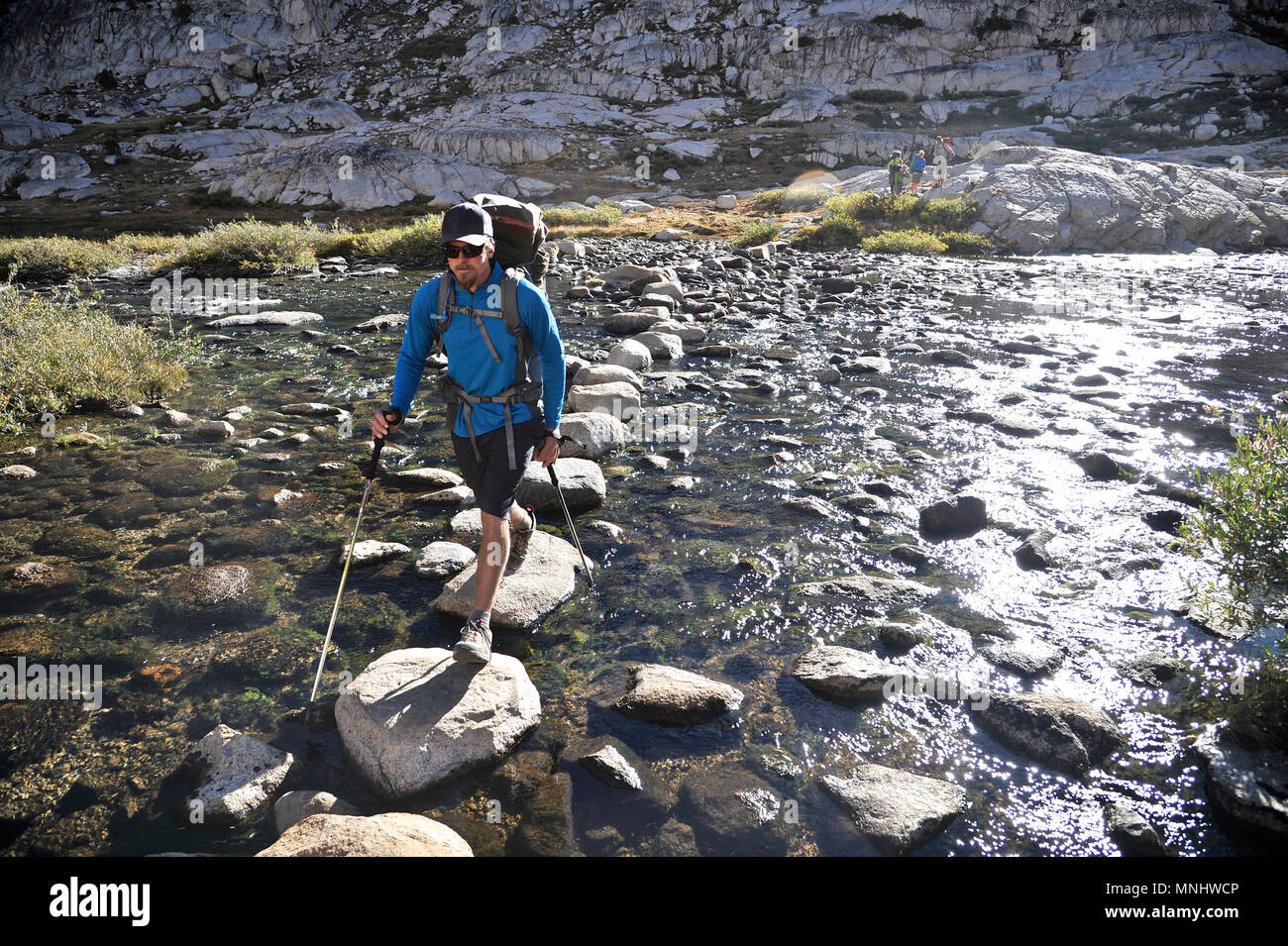 Backpacker hiking the John Muir Trail across Evolution Lake in the ...
