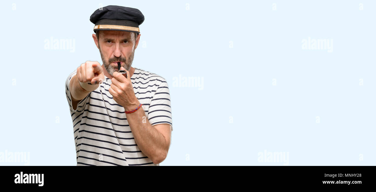 Sailor captain man smoking a tobacco pipe pointing to the front with ...