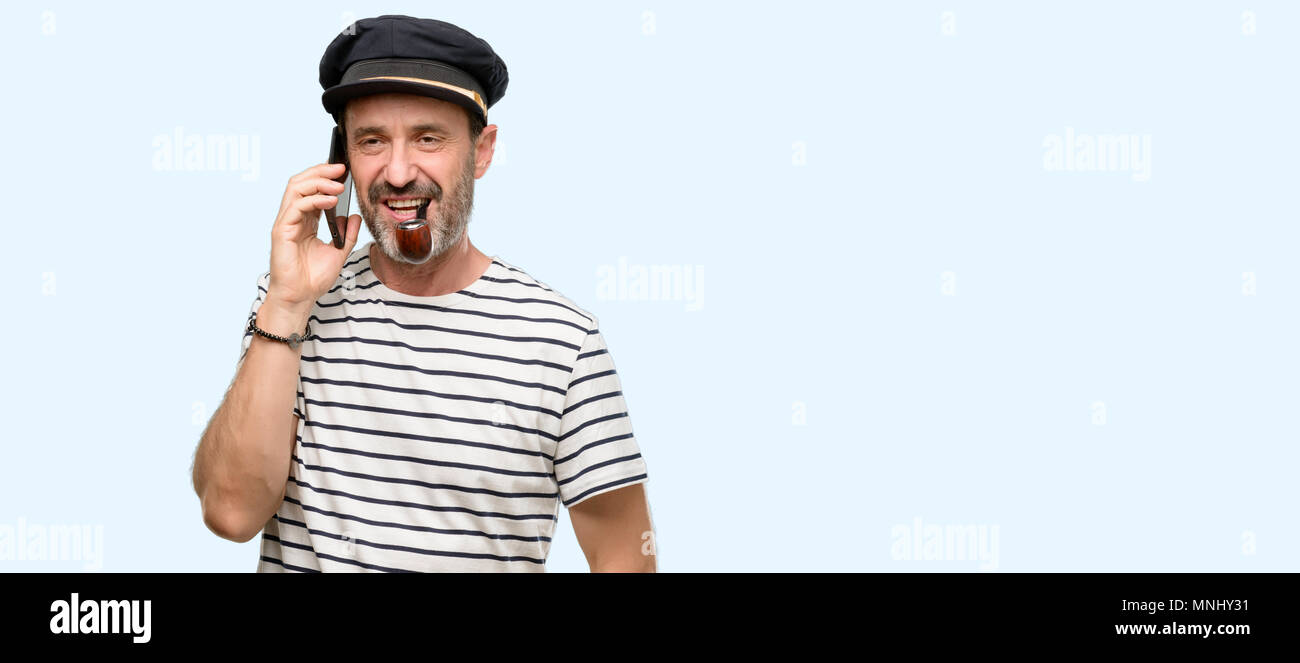 Sailor captain man smoking a tobacco pipe happy talking using a ...