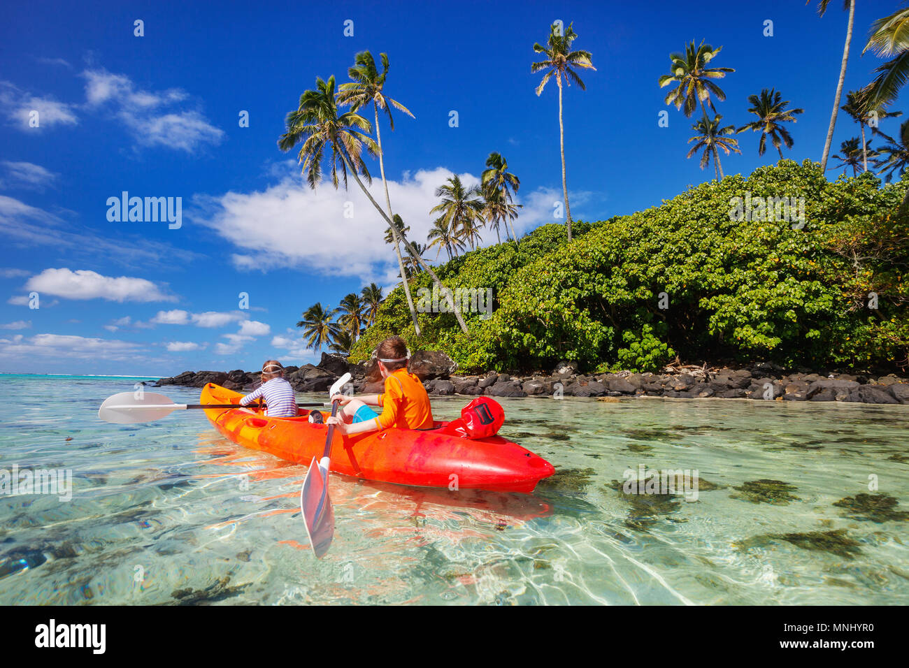Kids enjoying paddling in colorful red kayak at tropical ocean water ...
