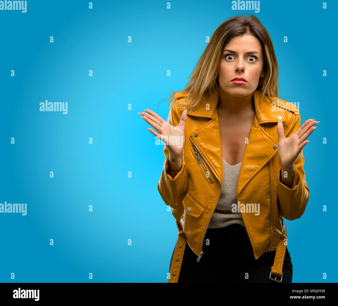 Beautiful young woman scared in shock, expressing panic and fear, blue ...