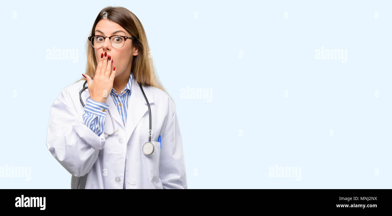 Young doctor woman, medical professional covers mouth in shock, looks ...