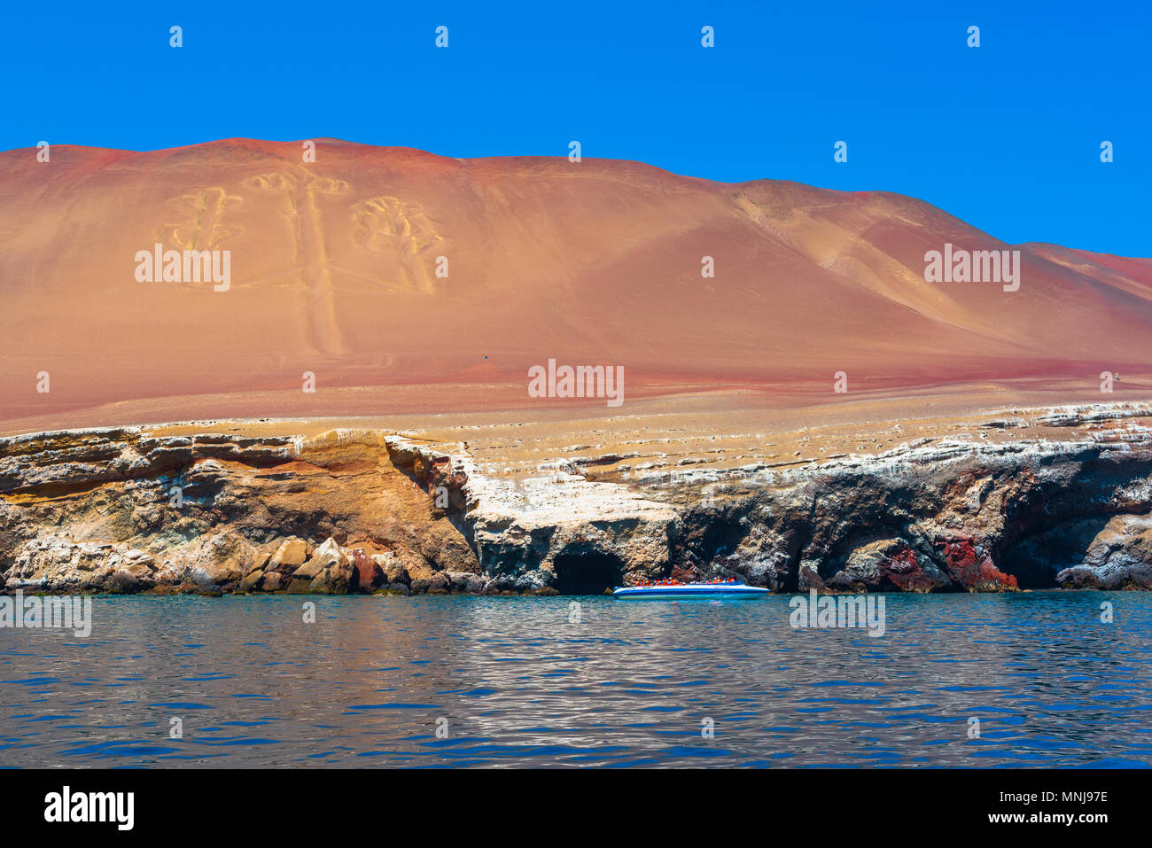 Paracas, Peru -- April 11, 2018. A tour boat hovers near desert caves ...