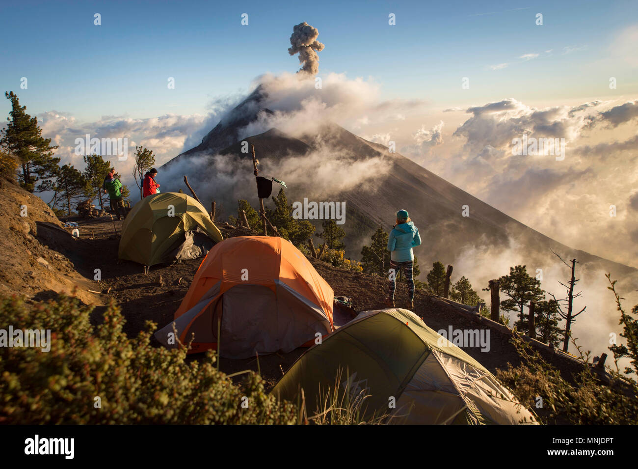 Small group of hikers looking at view of erupting Fuego Volcano near ...
