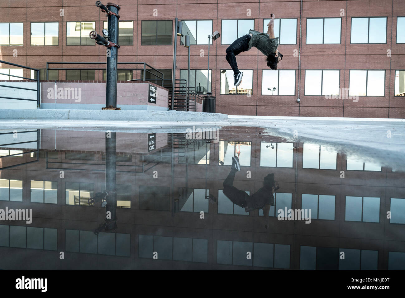 Park athlete in mid back flip in parking lot in downtown Denver ...