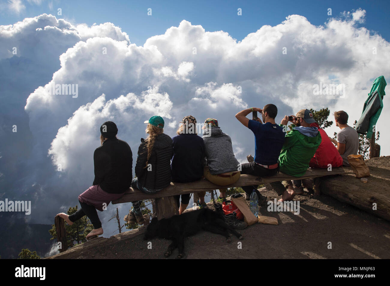 Rear view of group of hikers sitting on bench at summit of Acatenango ...