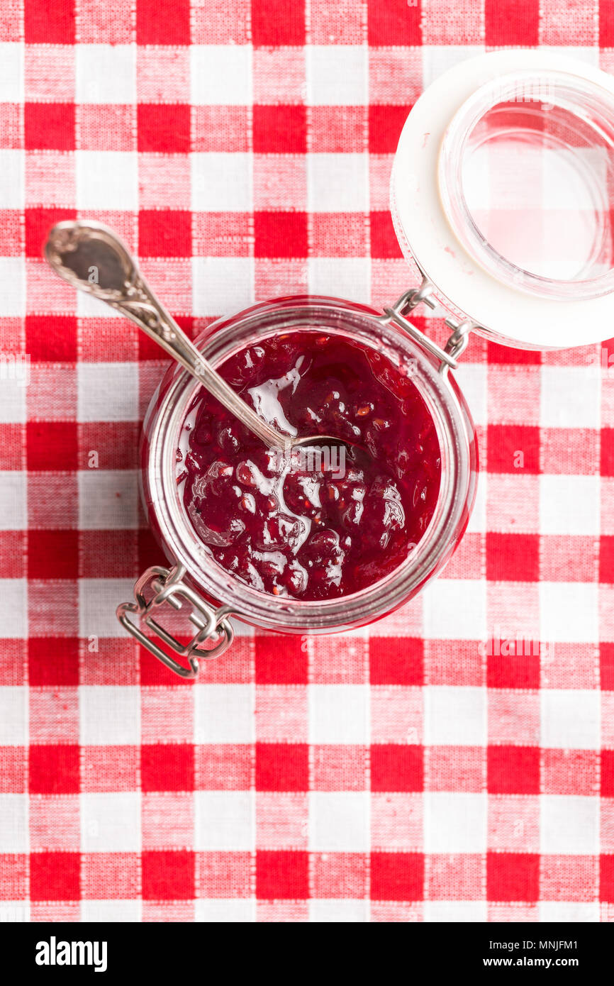 Raspberry jam jelly in jar on checkered tablecloth Stock Photo - Alamy