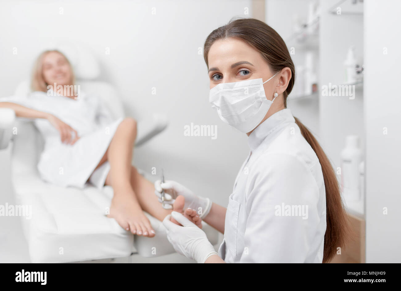 Podiatrist in mask on face looking at camera and working Stock Photo ...