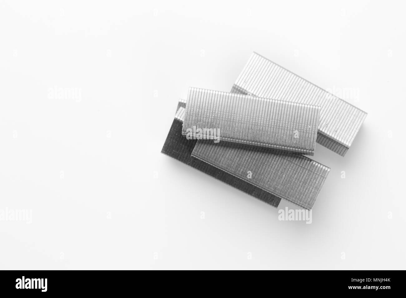Stripes of silver metal staples on a pile in front of a white ...