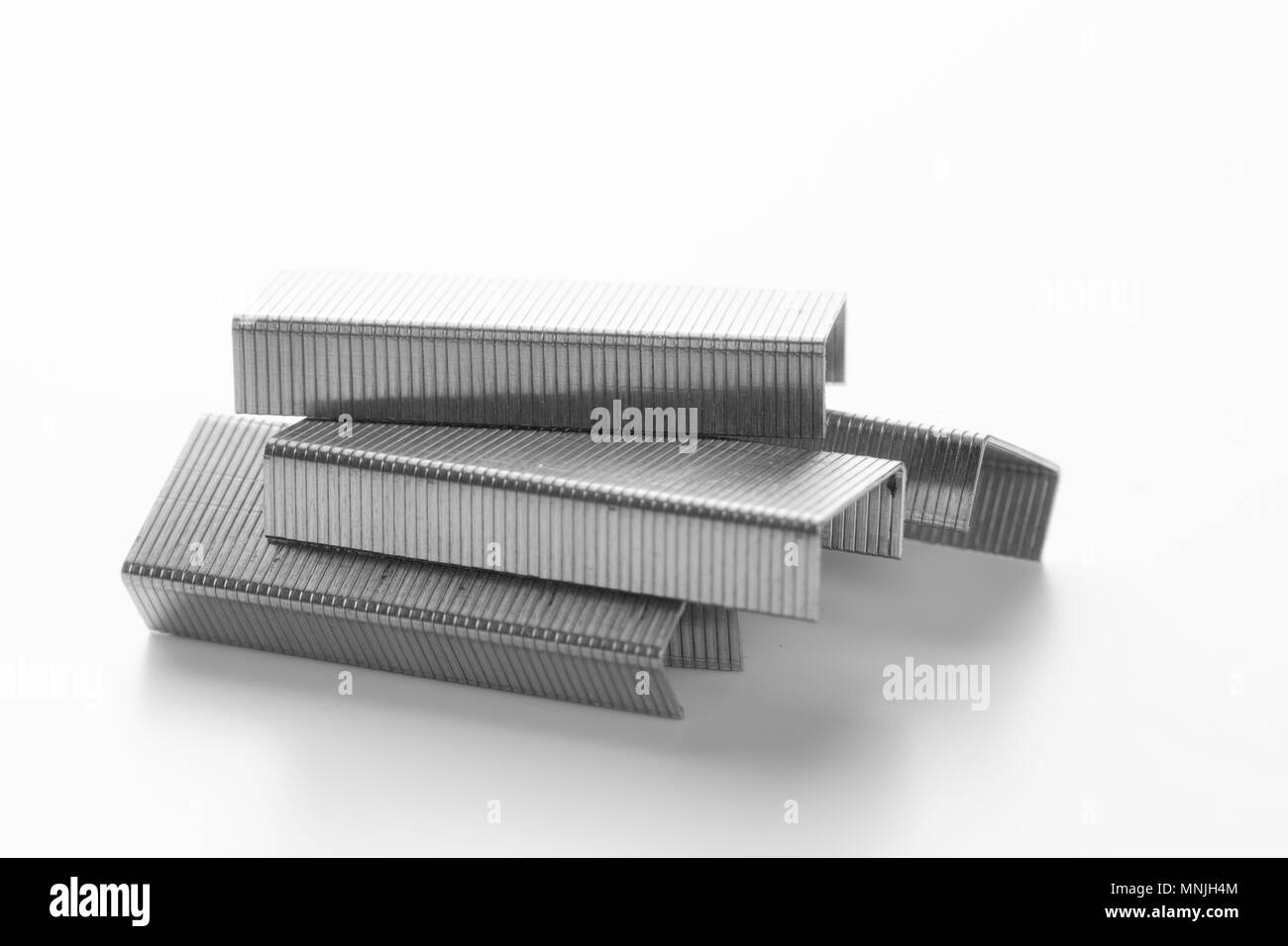 Stripes of silver metal staples on a pile against a white background ...