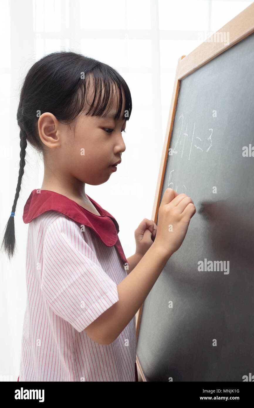 Asian Chinese little girl writing on blackboard in isolated white ...
