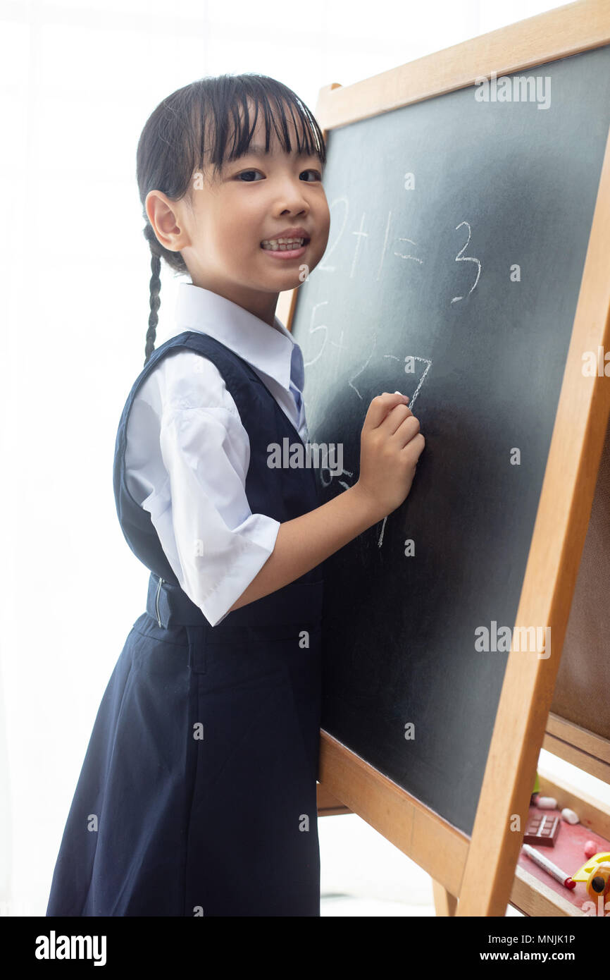 Asian Chinese little girl writing on blackboard in isolated white ...