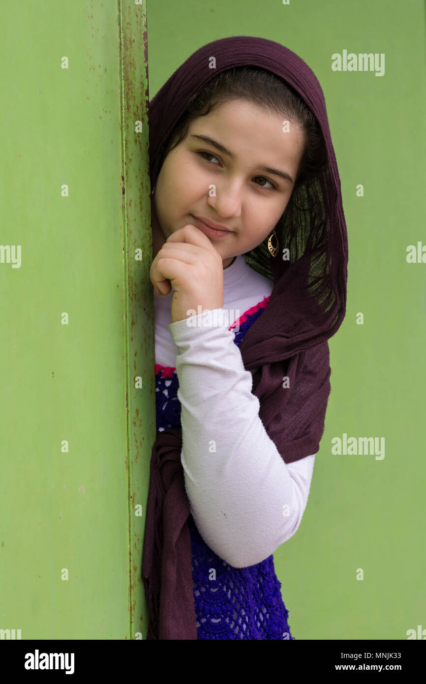 A close up portrait of a thinking beautiful girl in front of a green ...