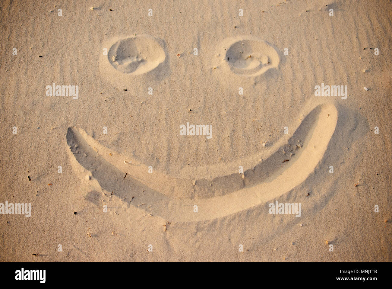 A smiley face drawing on a sand Stock Photo - Alamy