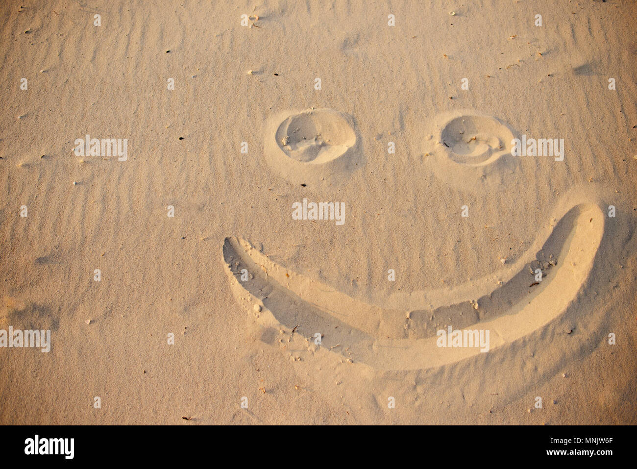 A smiley face drawing on a sand Stock Photo - Alamy