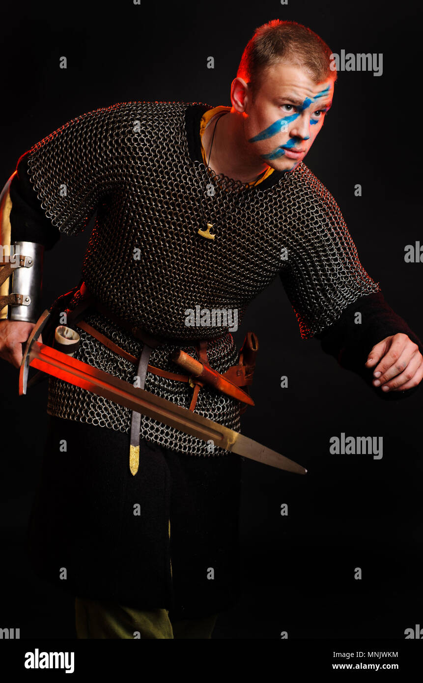 A soldier in a chain of letters stands with a sword in his hands on a ...