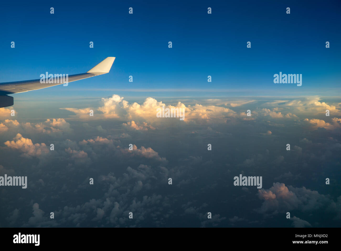 View out of airplane window with clouds at sunset and airplane wing ...