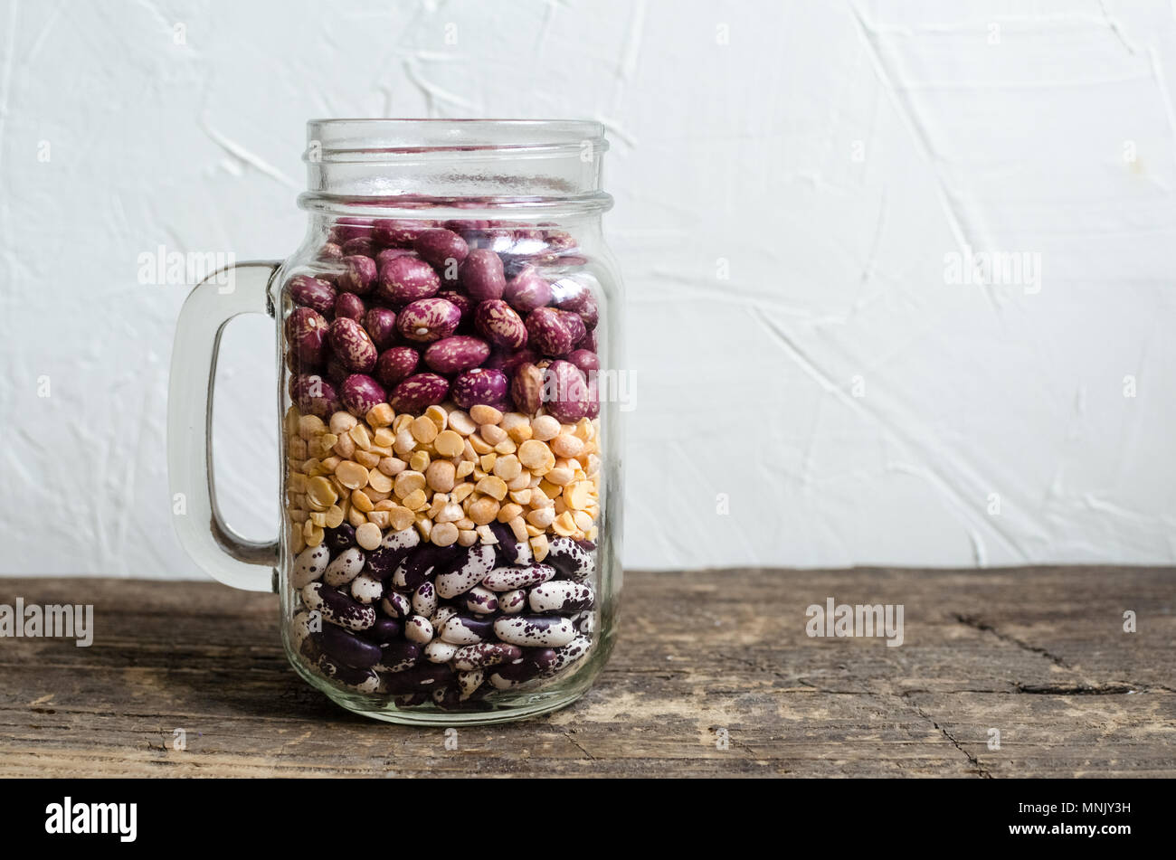 Assortment of dry organic beans and lentils layered in glass jar on ...