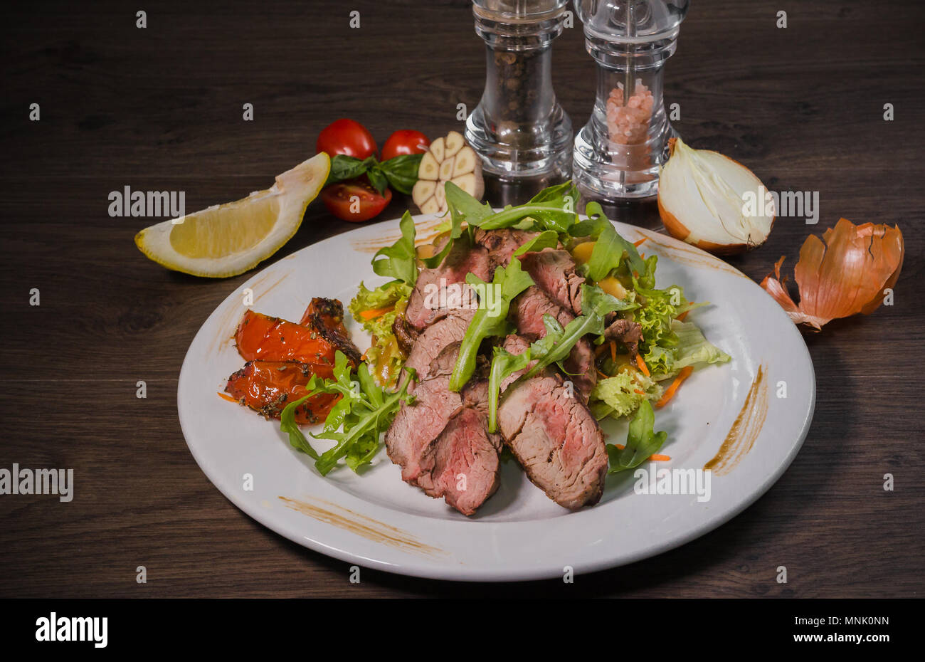 Roasted meat with blood in a cut with vegetables on a wooden background ...
