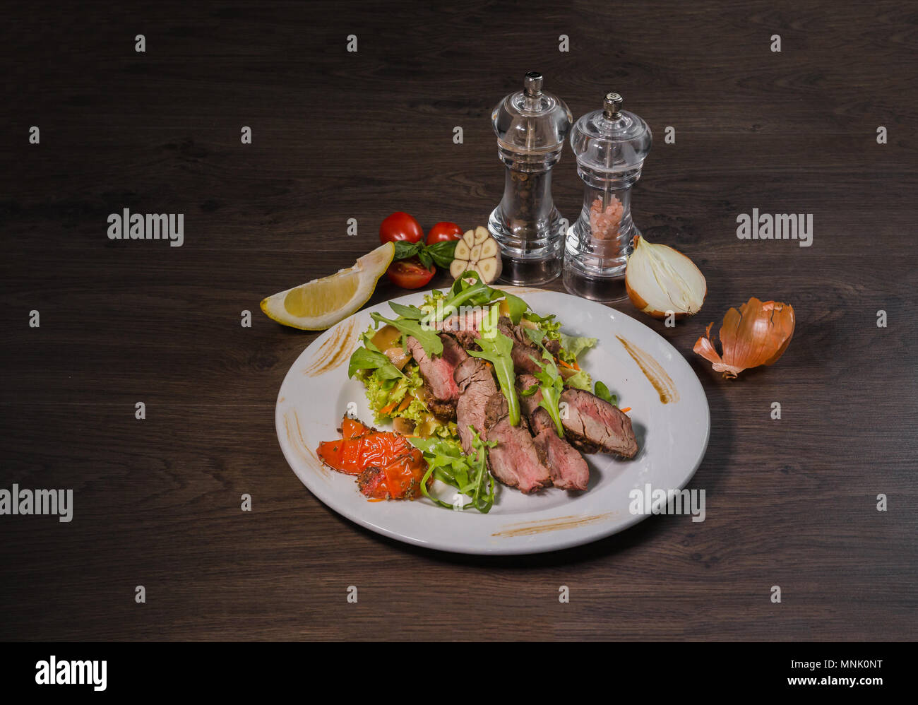 Roasted meat with blood in a cut with vegetables on a wooden background ...