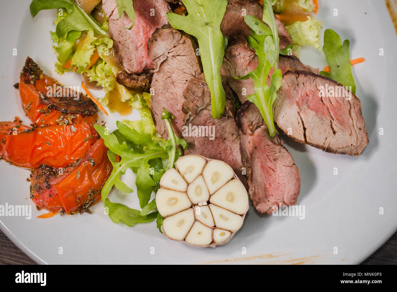 Roasted meat with blood in a cut with vegetables on a wooden background ...