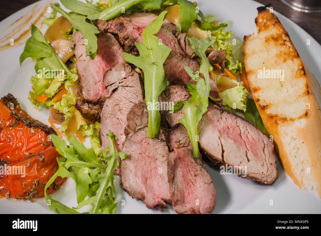 Roasted meat with blood in a cut with vegetables on a wooden background ...