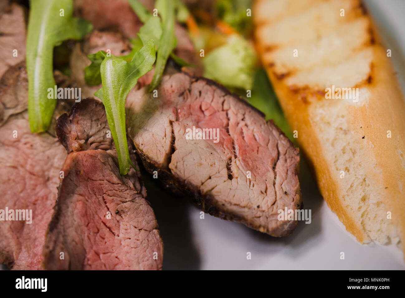 Roasted meat with blood in a cut with vegetables on a wooden background ...