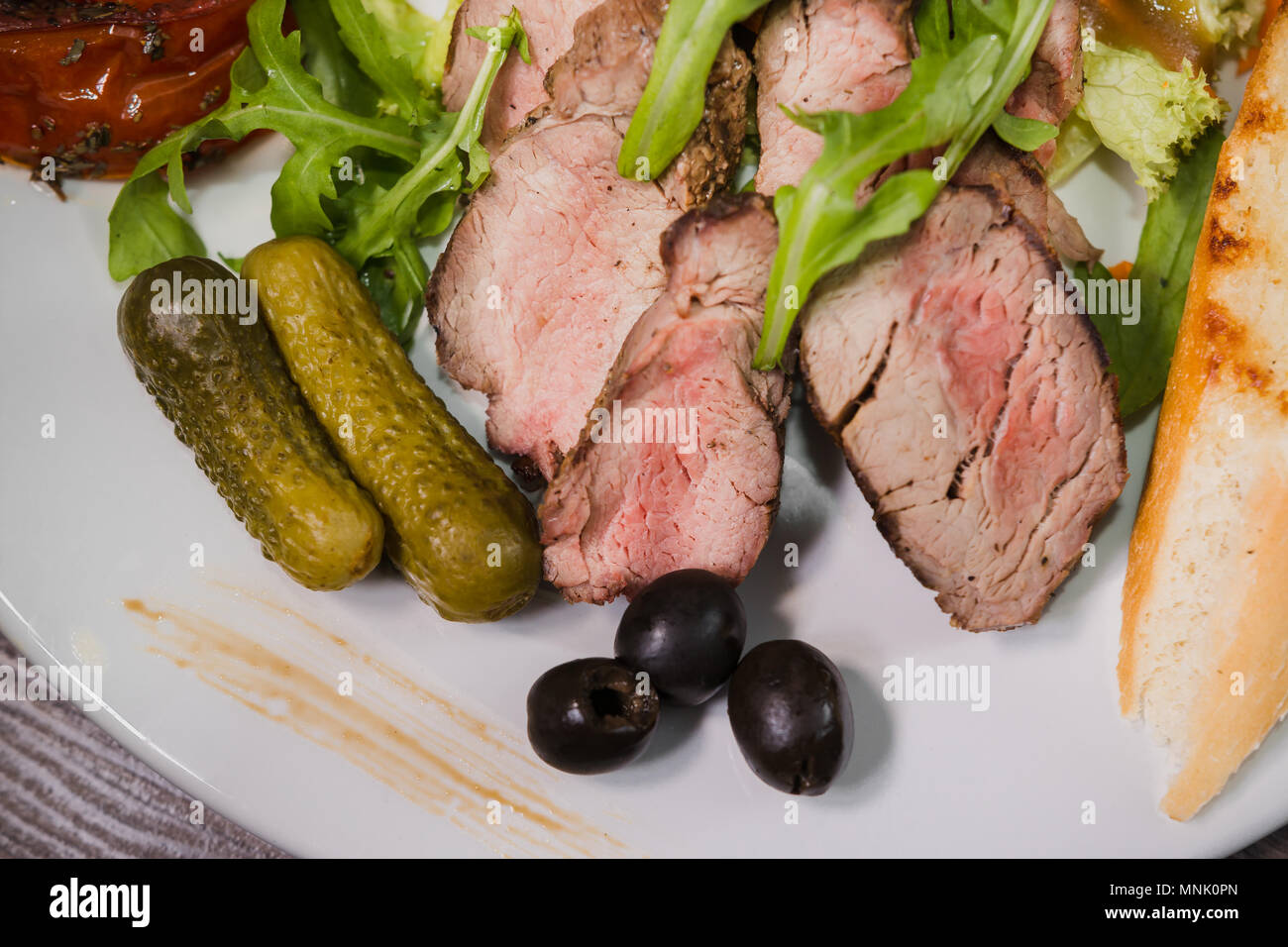 Roasted meat with blood in a cut with vegetables on a wooden background ...