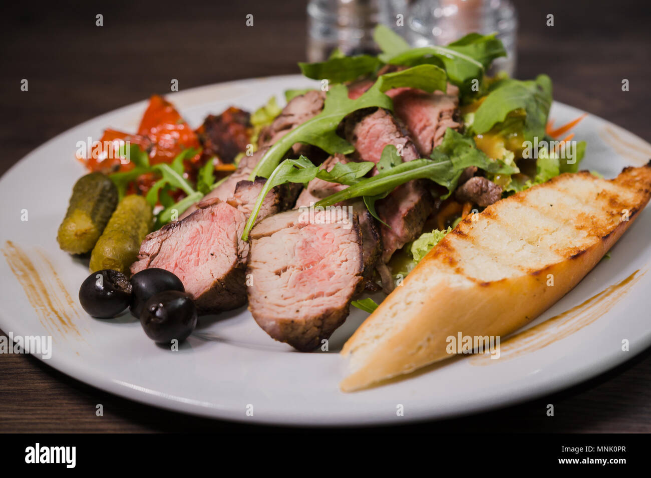 Roasted meat with blood in a cut with vegetables on a wooden background ...